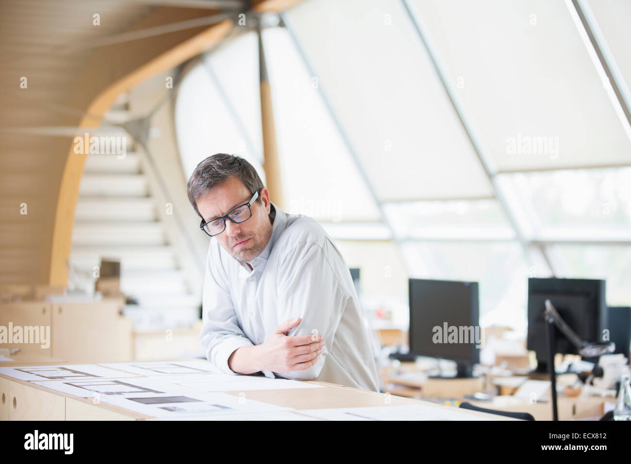 Businessman reading paperwork at office desk Stock Photo - Alamy