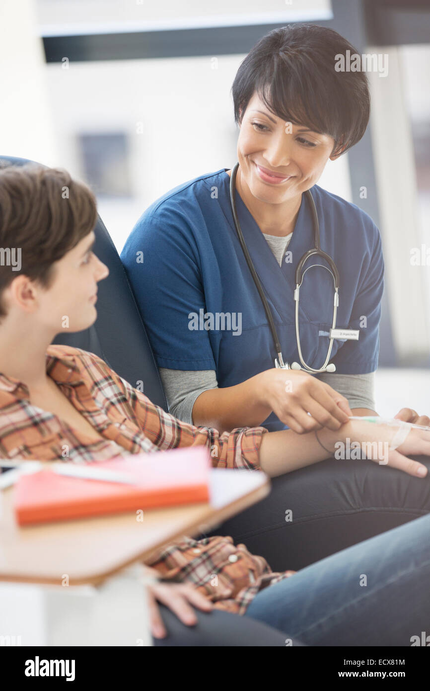 Female doctor talking to young patient receiving medical treatment in ...