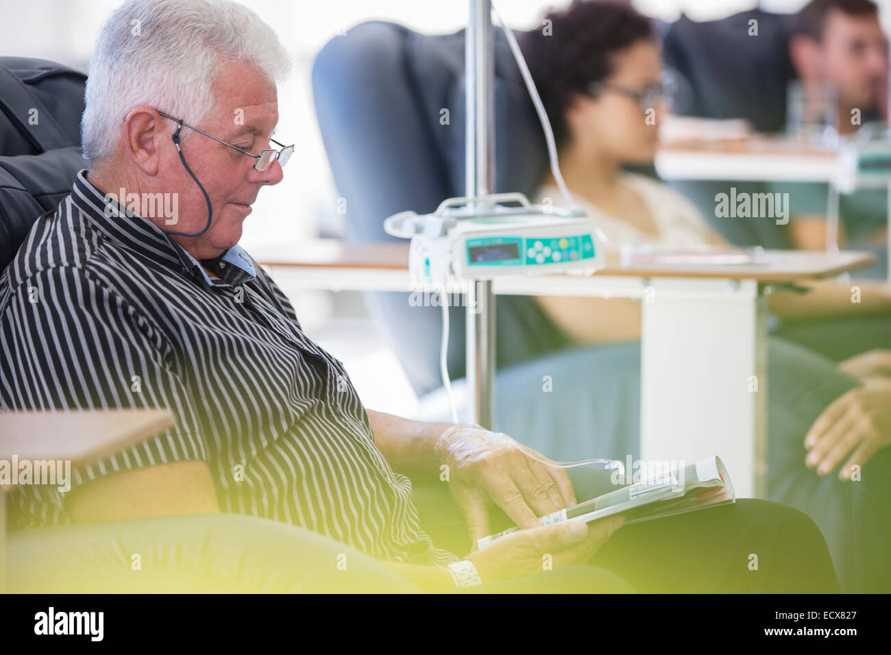 Senior patient receiving treatment while sitting and reading book in ...
