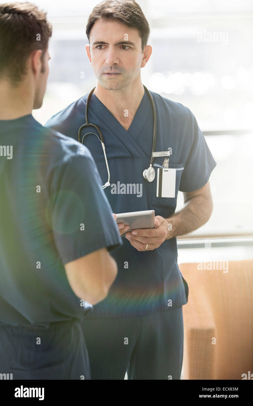 Two male doctors talking, one holding tablet pc Stock Photo - Alamy