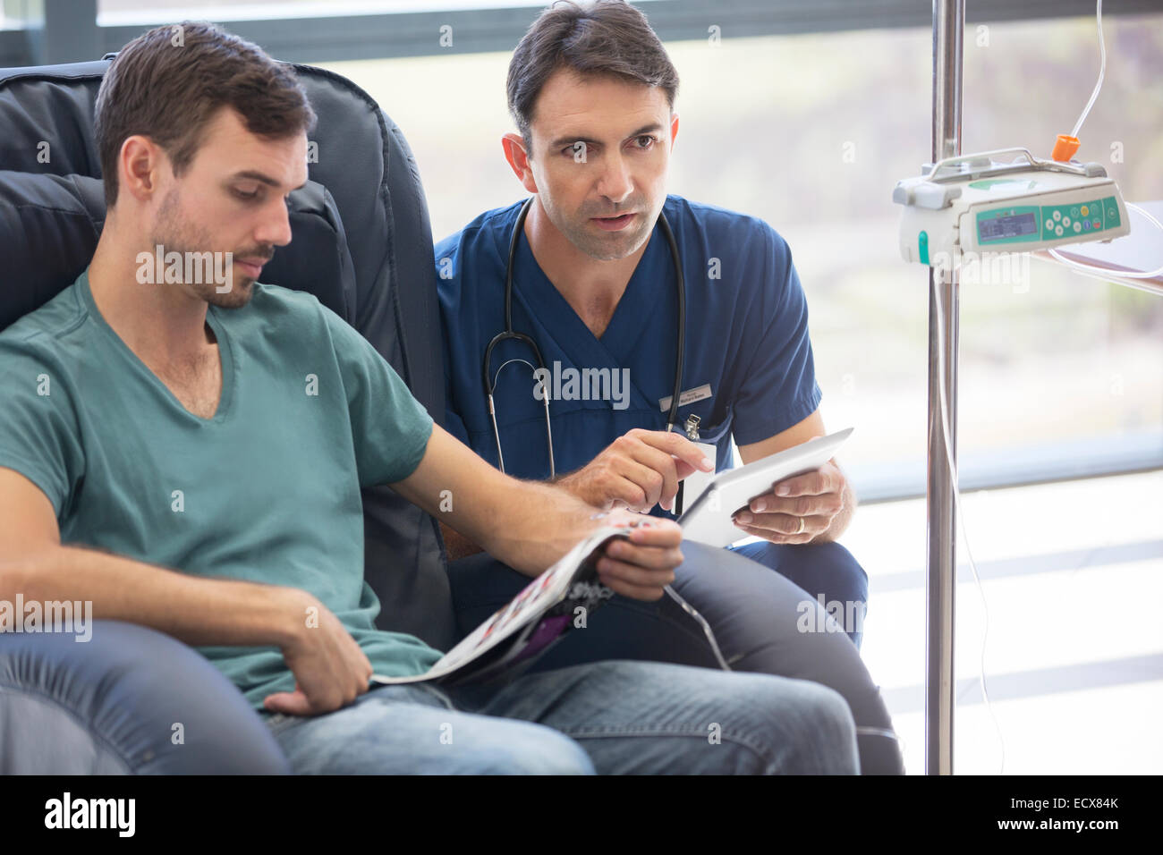 Doctor holding digital tablet, talking to patient undergoing medical ...