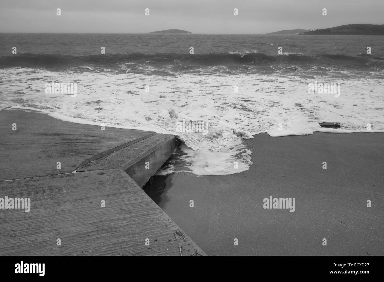 The sea breaks over a slip way in winter on Abersoch Beach, North Wales ...