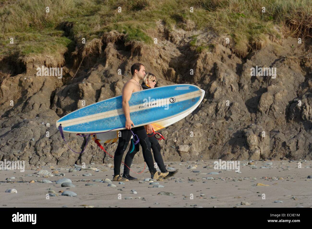 Good conditions for surfing in North Wales. A Couple carry their long ...