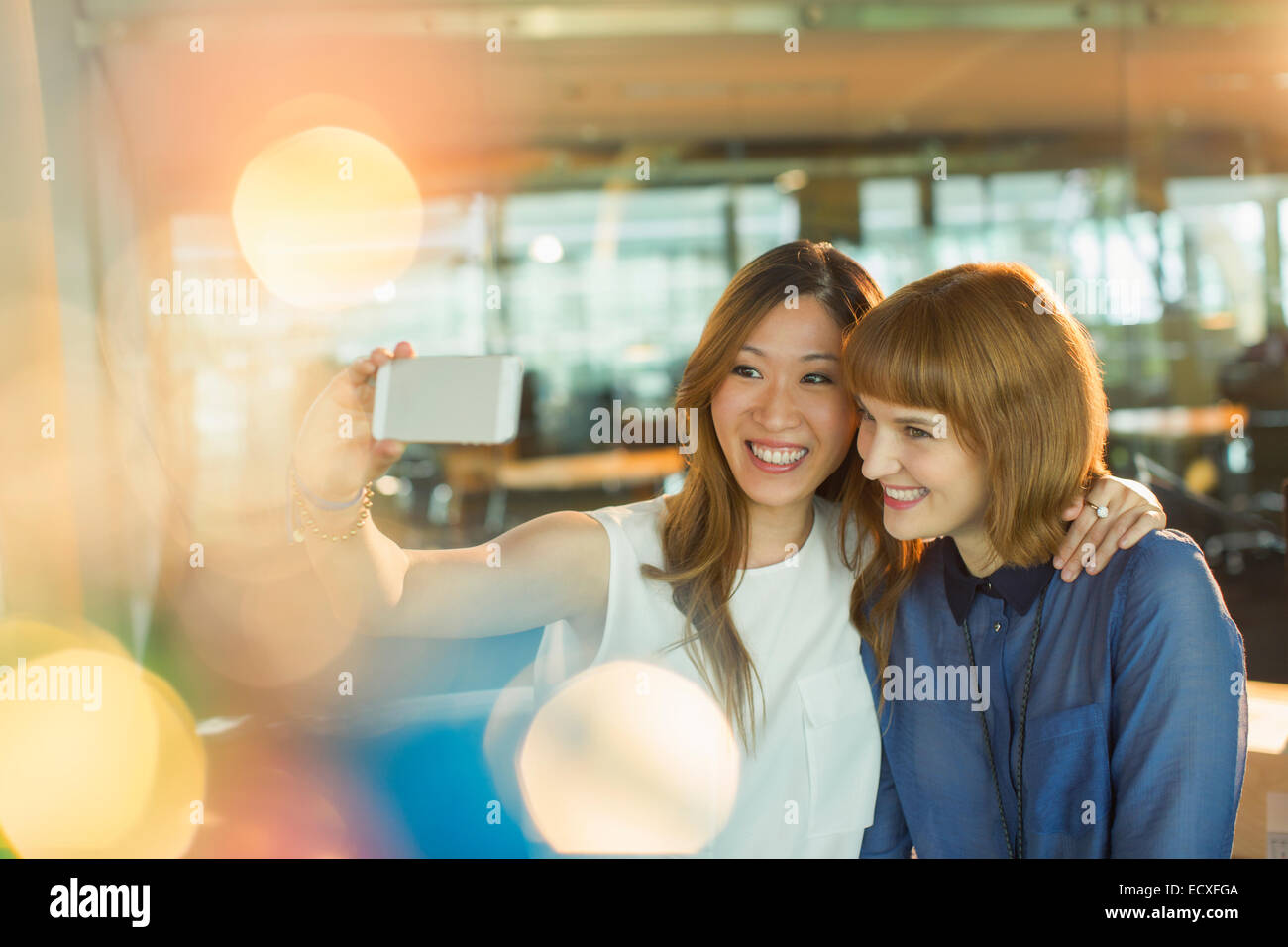 Businesswomen taking cell phone selfie in office Stock Photo - Alamy