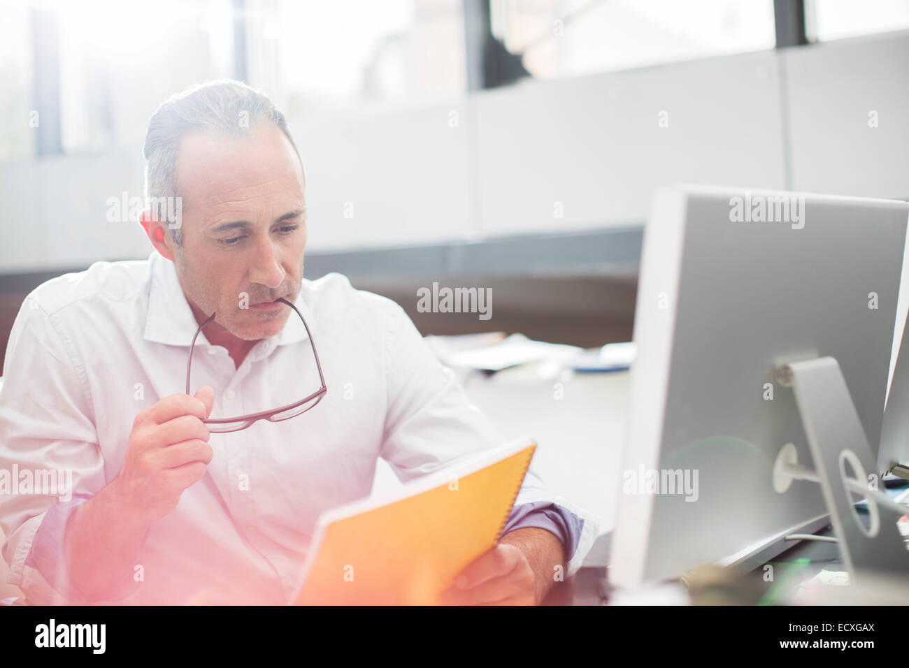 Businessman reading paperwork at office desk Stock Photo - Alamy