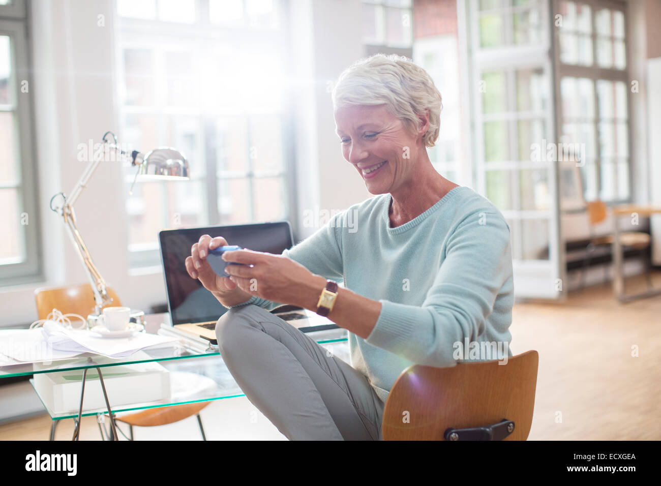 Businesswoman using cell phone at home office desk Stock Photo - Alamy