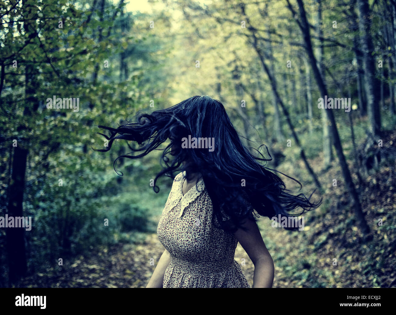 Scared young woman running through a forest at night, looking back ...