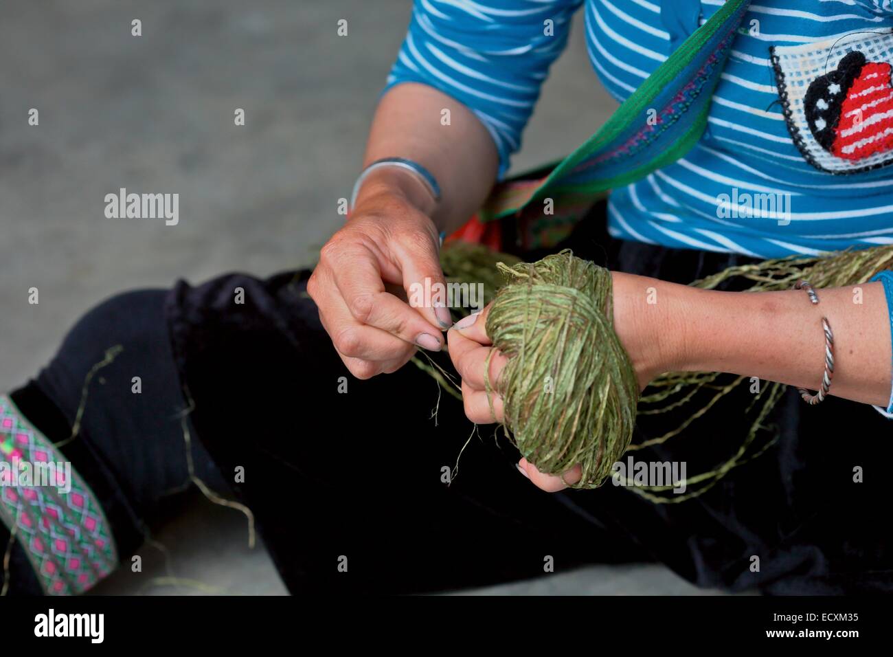 A Hmong woman hand spins hemp prior to dying it black and weaving ...
