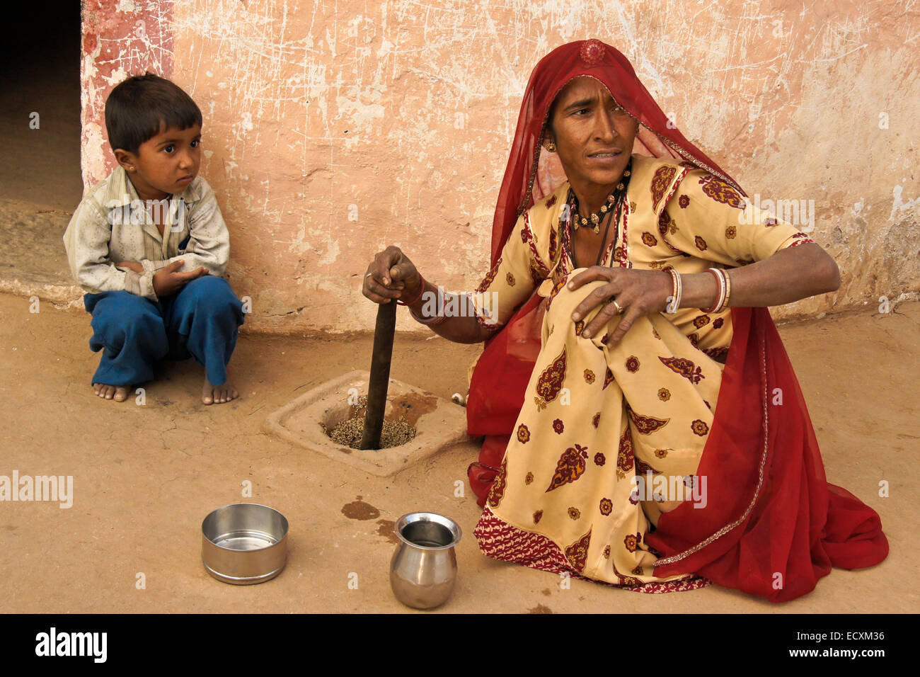 Nagauri Jat woman (pounding millet) and child, Rajasthan, India Stock ...