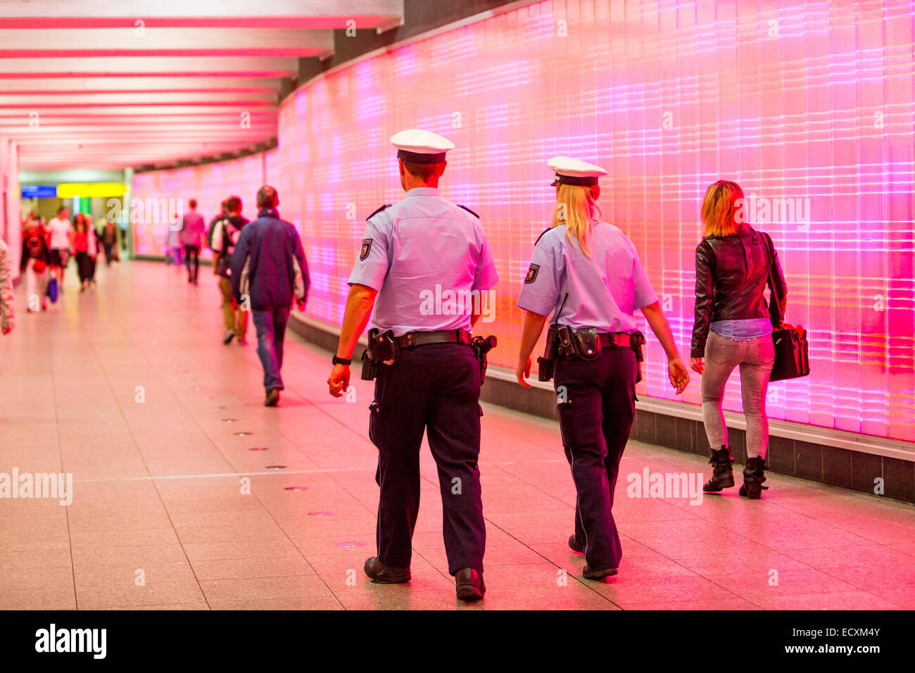 Passengers in an underground passage with a wall of lights, police ...