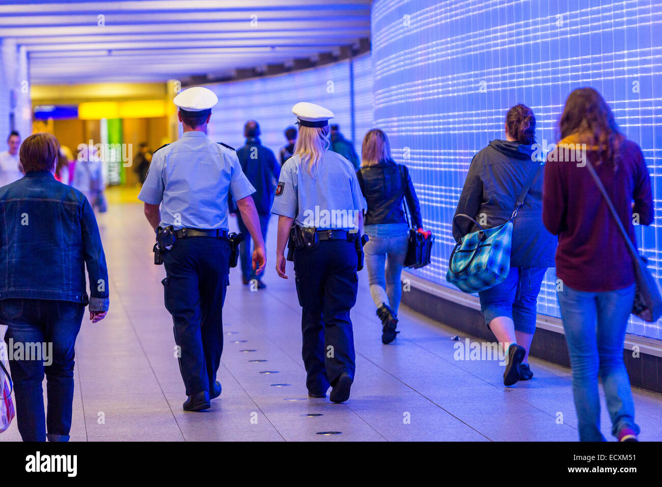 Passengers in an underground passage with a wall of lights, police ...