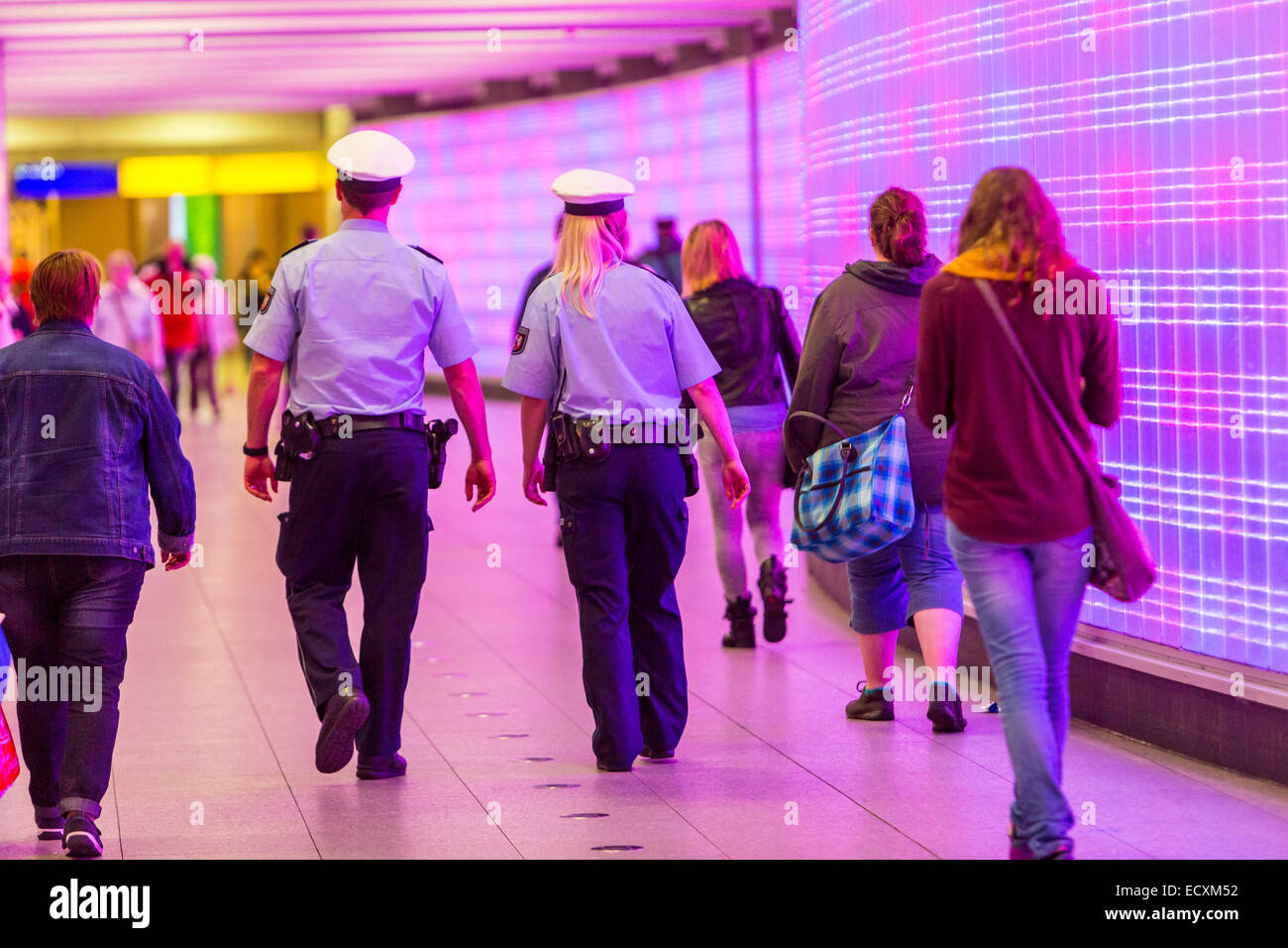 Passengers in an underground passage with a wall of lights, police ...