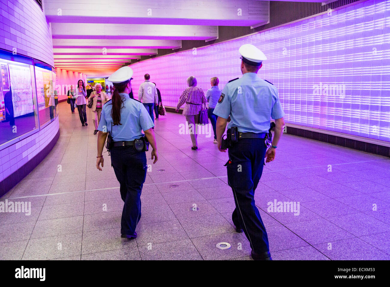 Passengers in an underground passage with a wall of lights, police ...