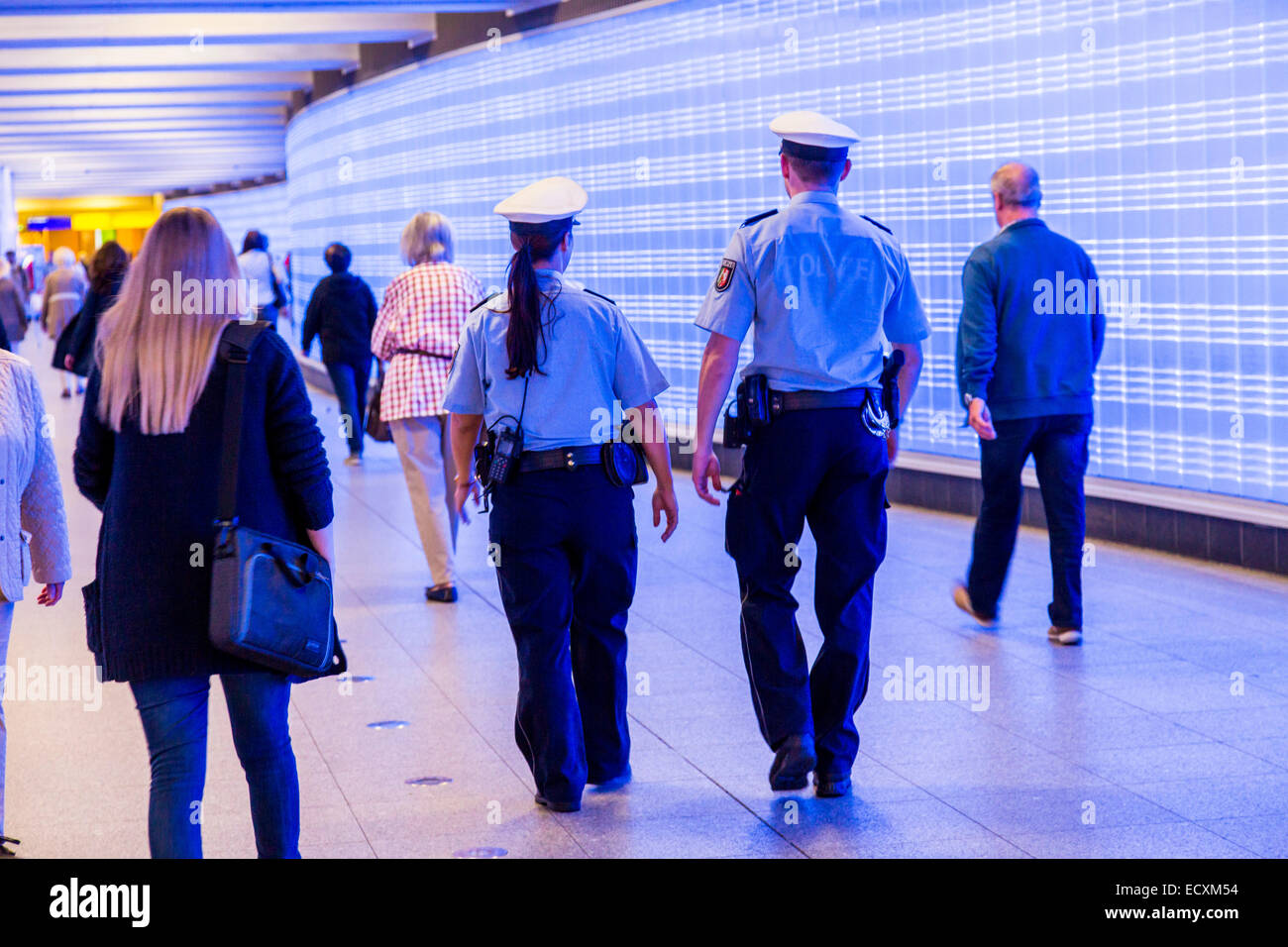 Passengers in an underground passage with a wall of lights, police ...