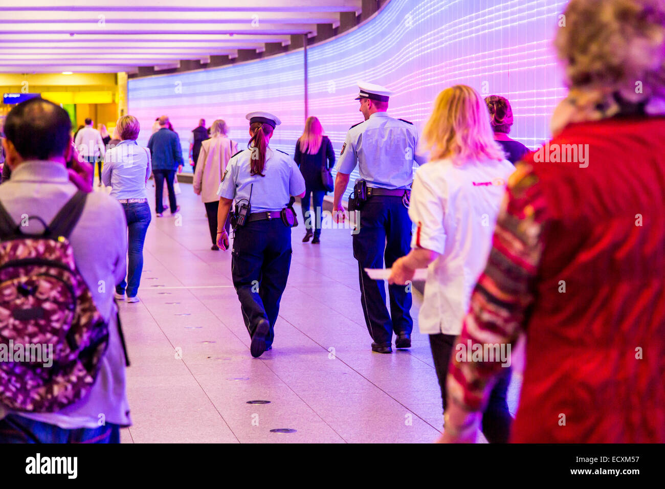 Passengers in an underground passage with a wall of lights, police ...