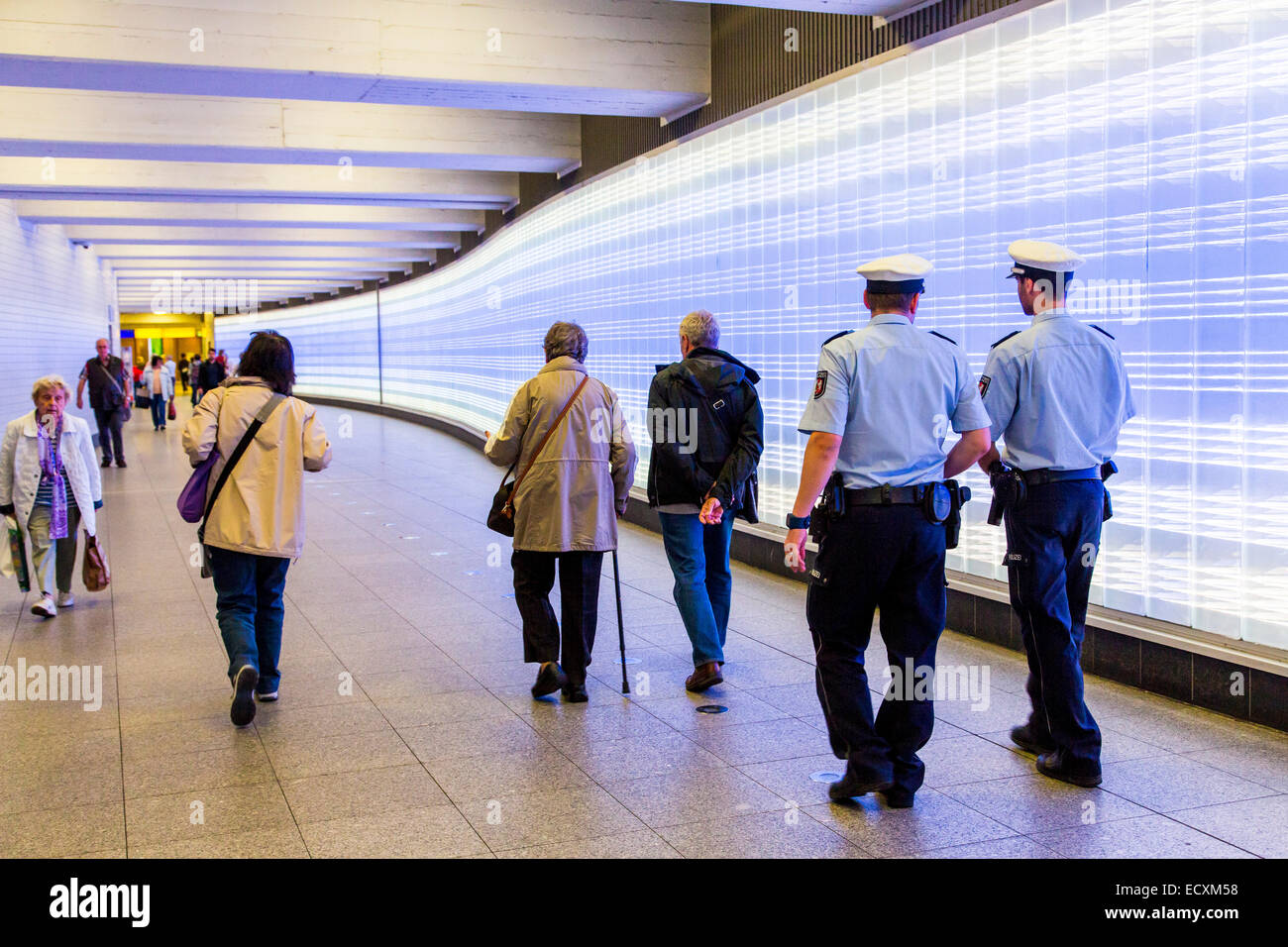 Passengers in an underground passage with a wall of lights, police ...