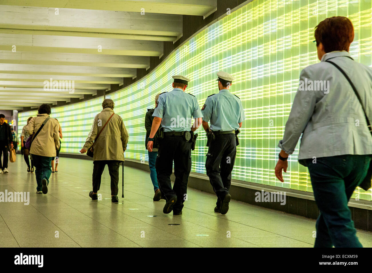 Passengers in an underground passage with a wall of lights, police ...