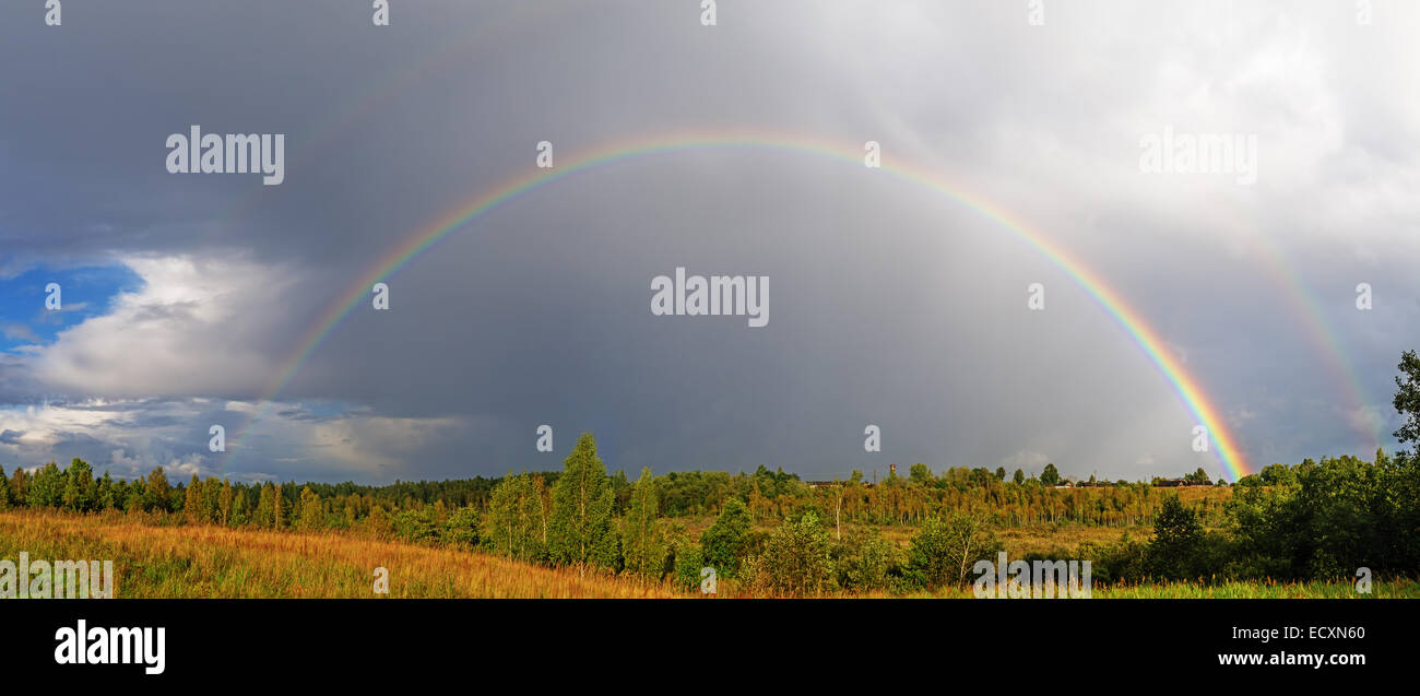 A bright double rainbow arches over a village field Stock Photo - Alamy