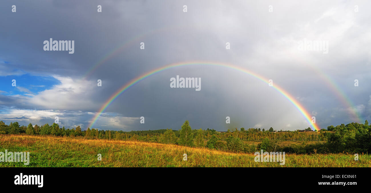 A bright double rainbow arches over a village field Stock Photo - Alamy