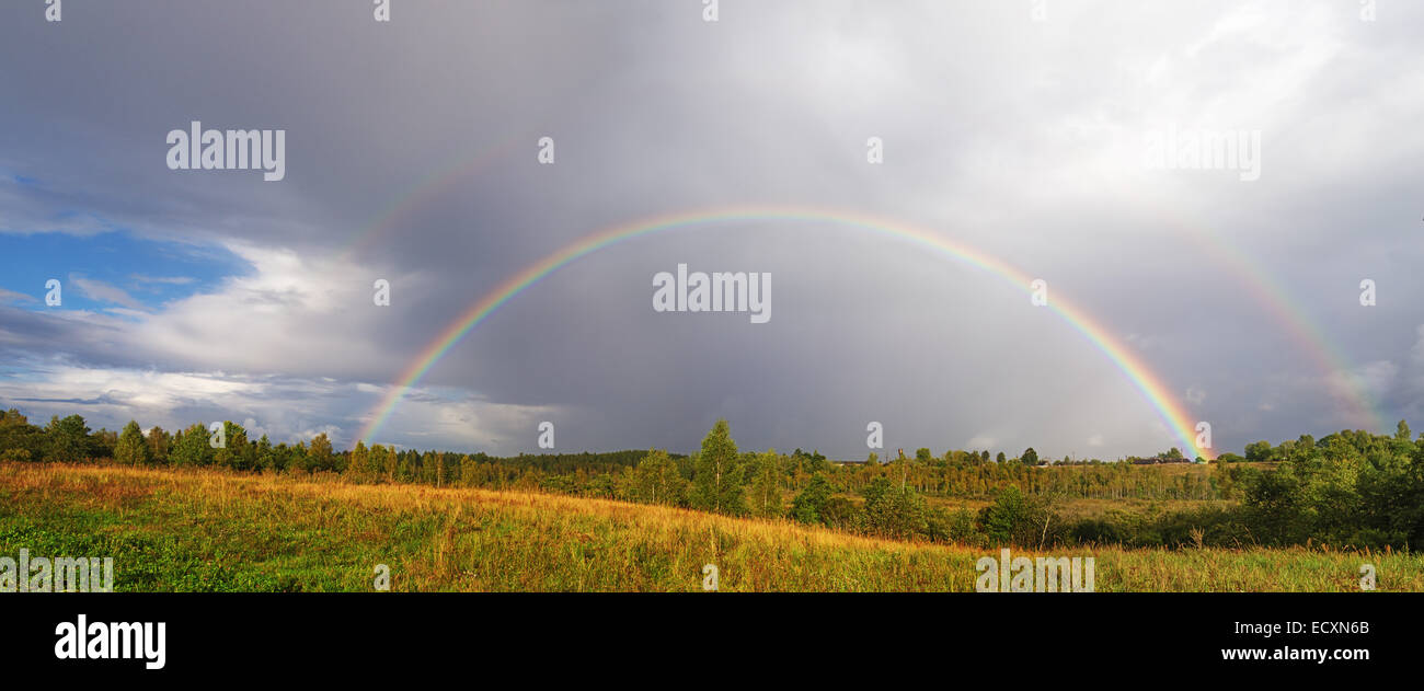 A bright double rainbow arches over a village field Stock Photo - Alamy