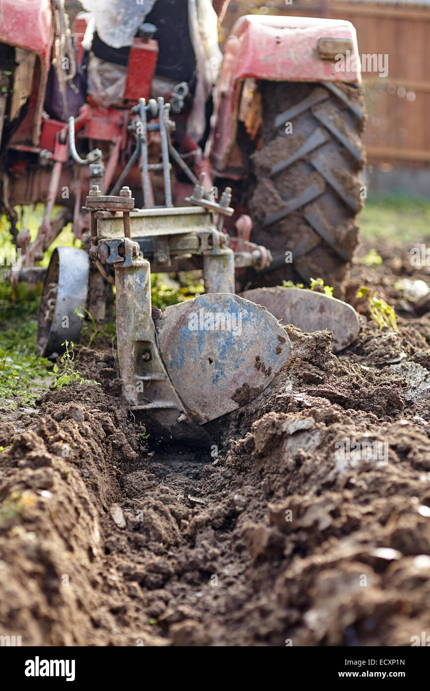 Image from the back of a tractor plowing the land, focus is on plow ...