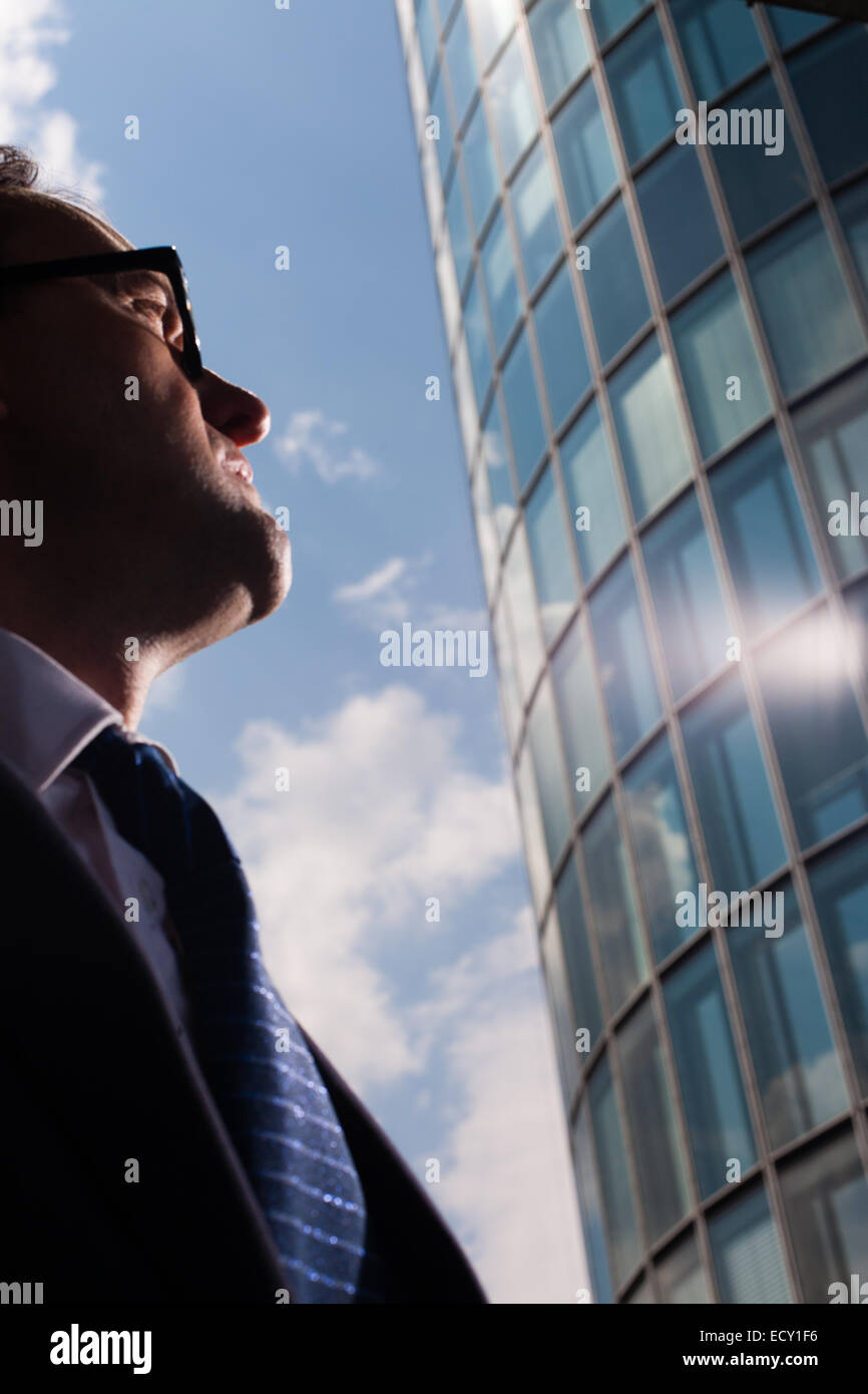 European business man in a suit with a high rise office building in the ...