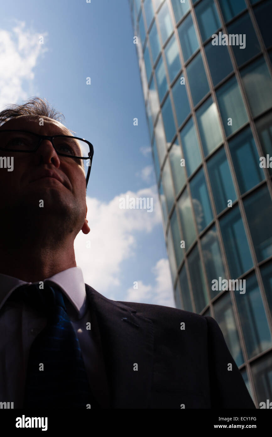 European business man in a suit with a high rise office building in the ...