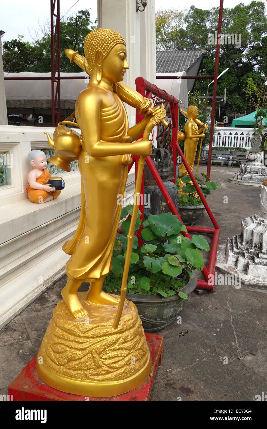 Statue of a walking pilgrim Buddha with umbrella and cane in front of ...