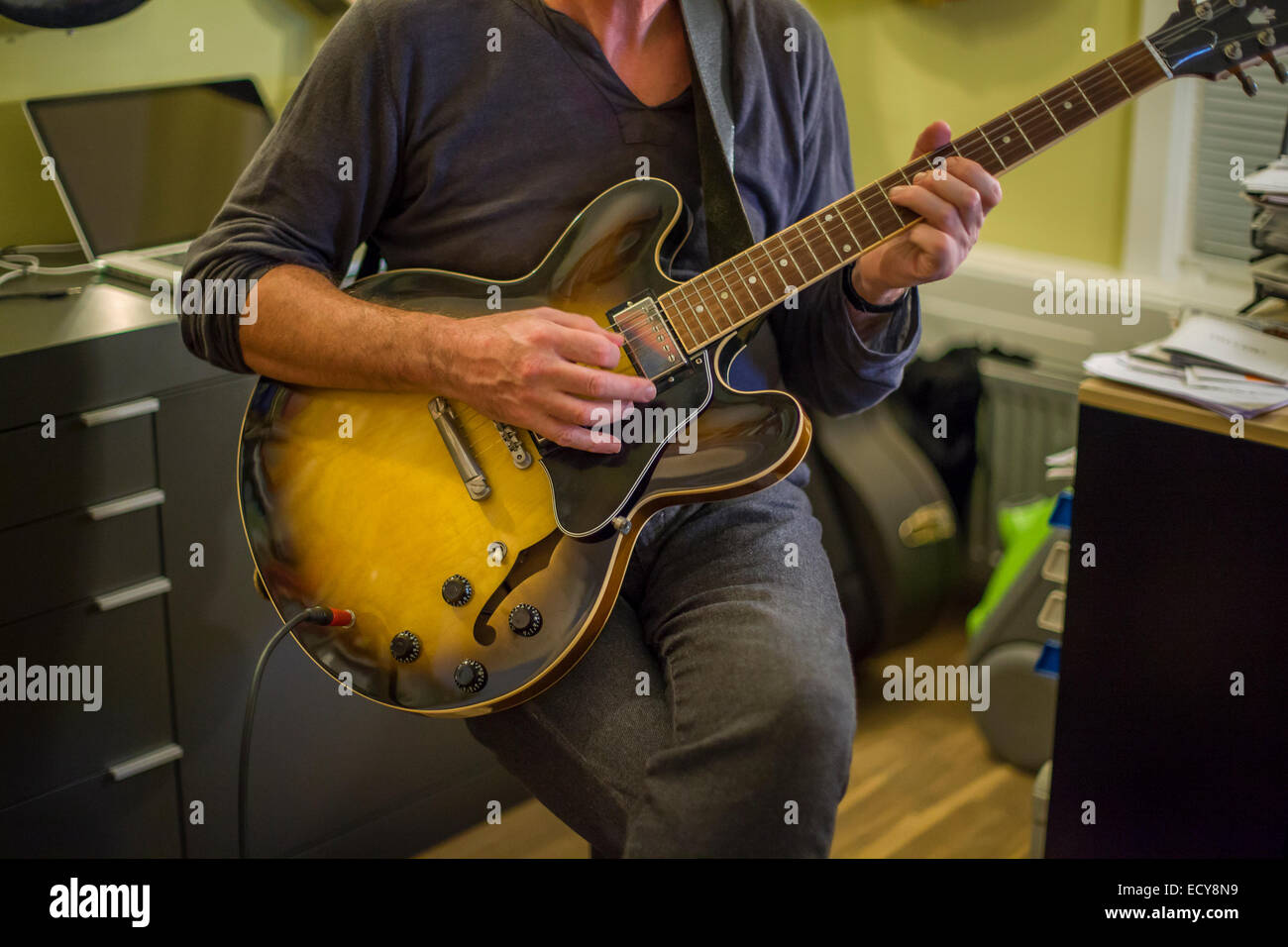 Man playing guitar inside room Stock Photo - Alamy