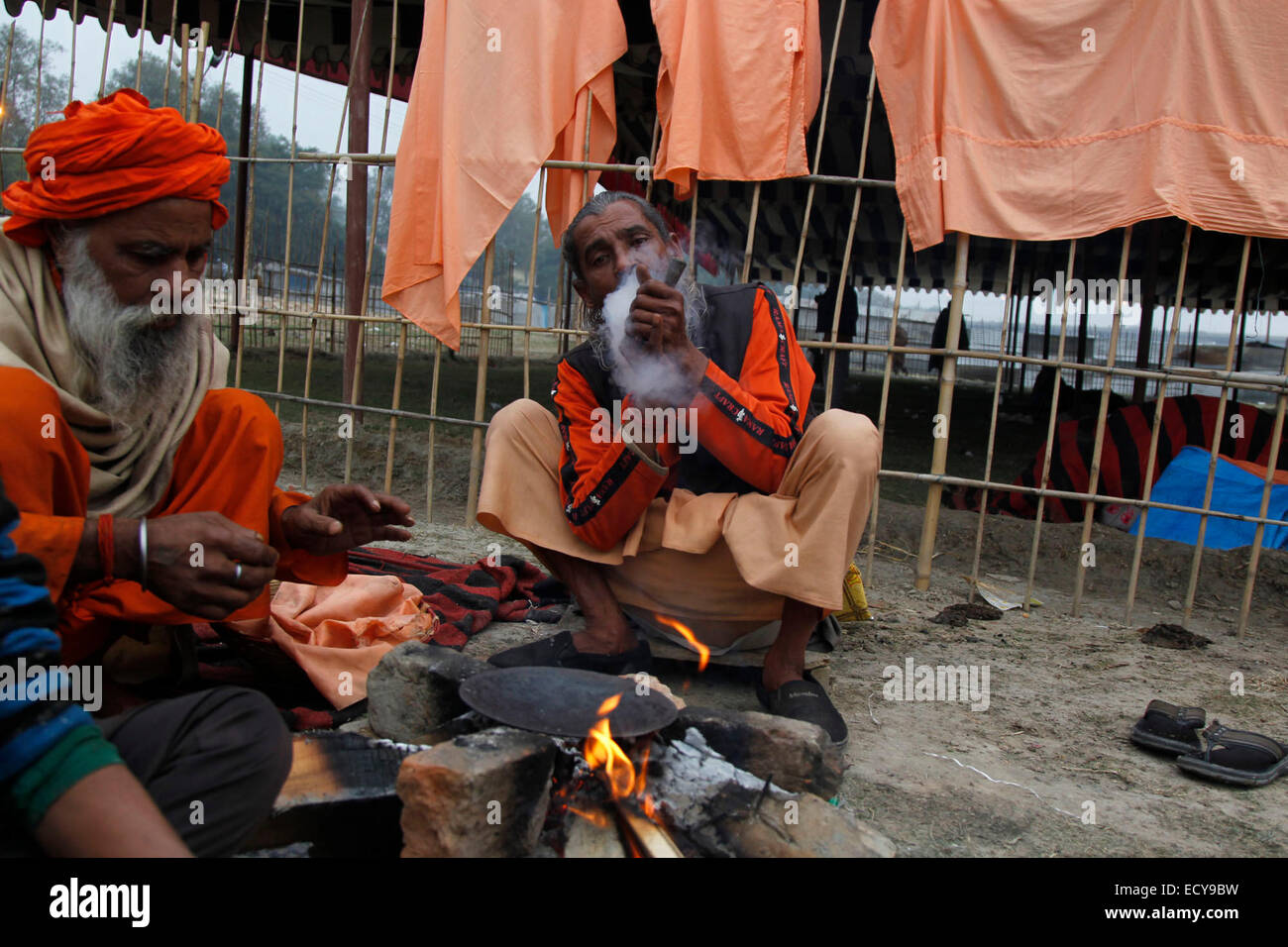 Sadhu or holy man puffing chillum on a foggy and cold day on the river ...
