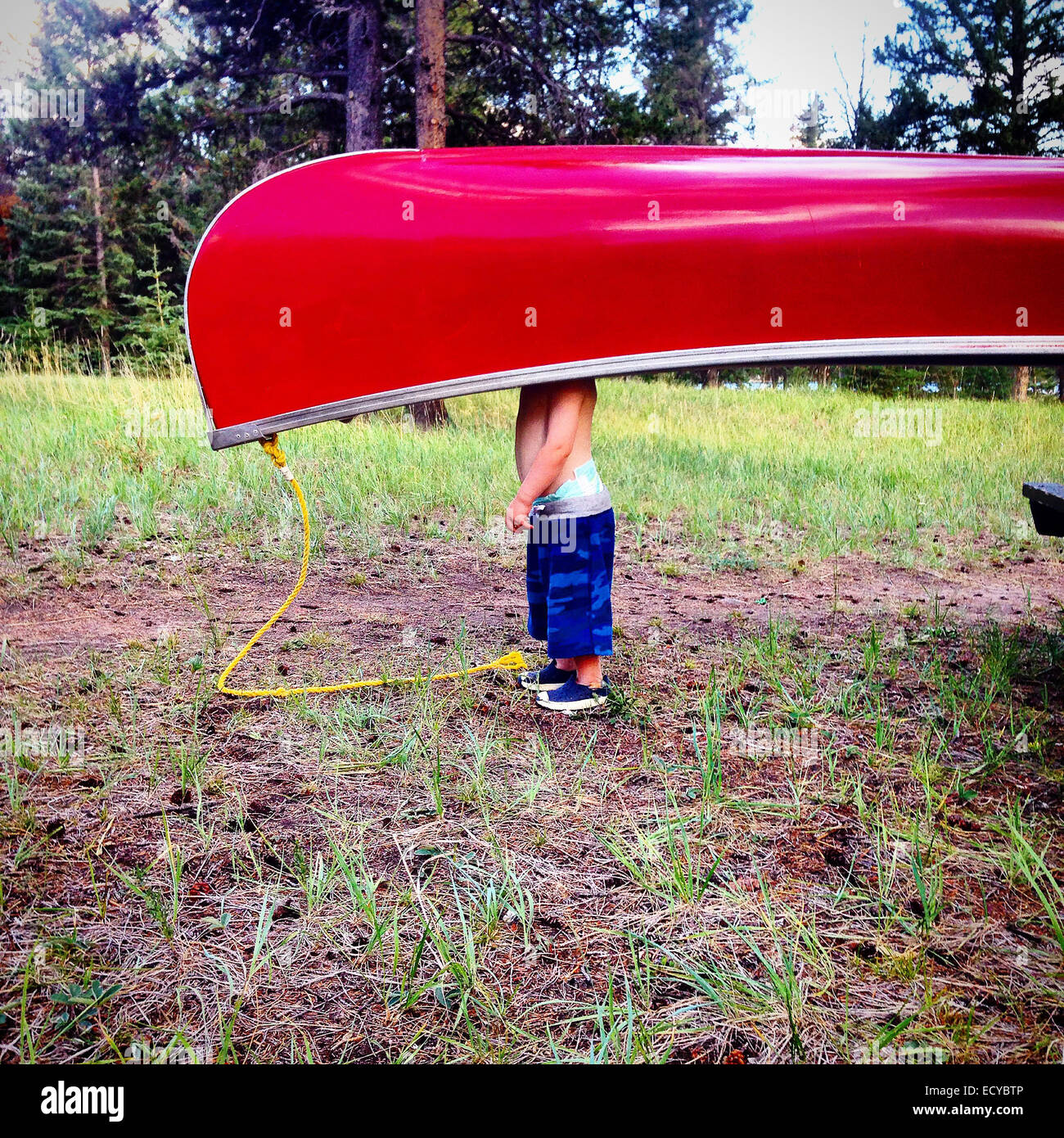 Caucasian boy carrying canoe in field Stock Photo - Alamy
