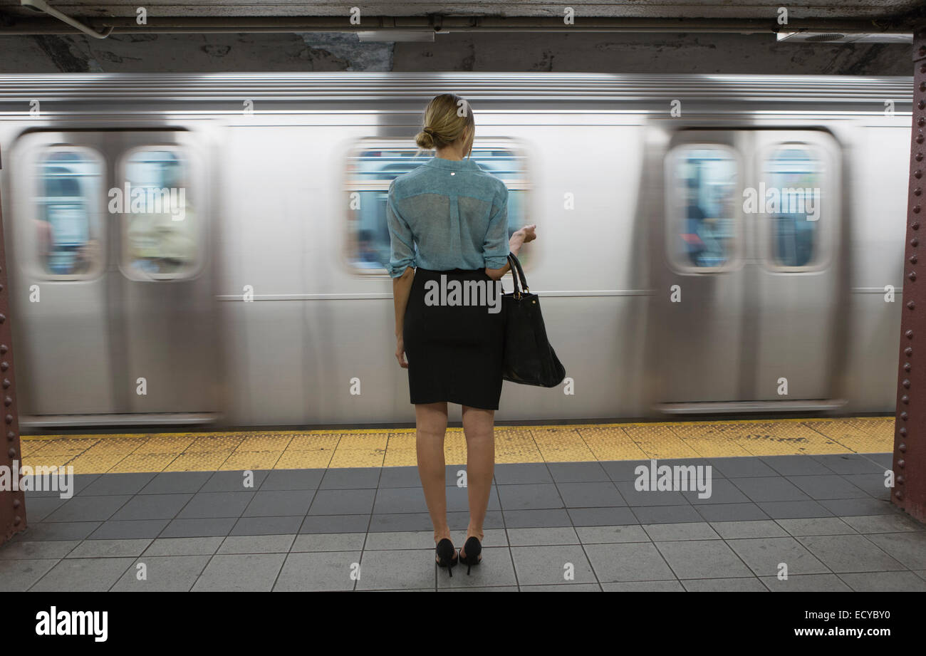 Caucasian woman standing near passing subway in train station Stock ...