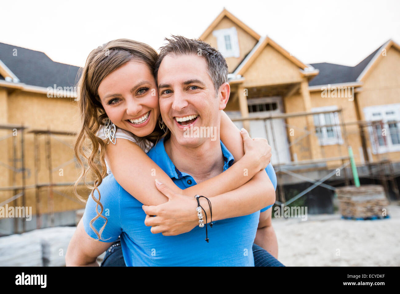 Caucasian couple hugging near house under construction Stock Photo - Alamy