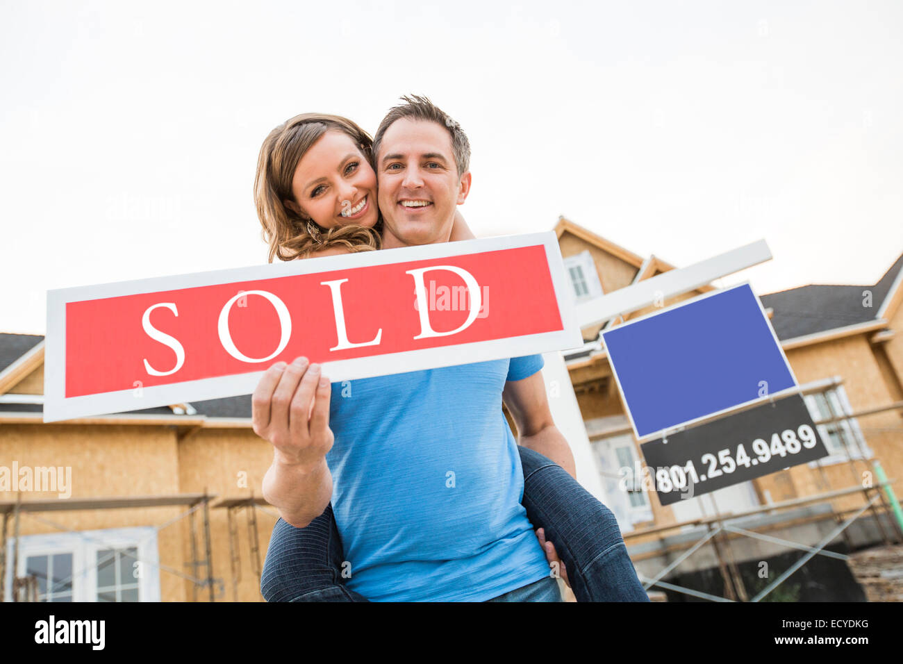 Caucasian couple holding sold sign near house under construction Stock ...