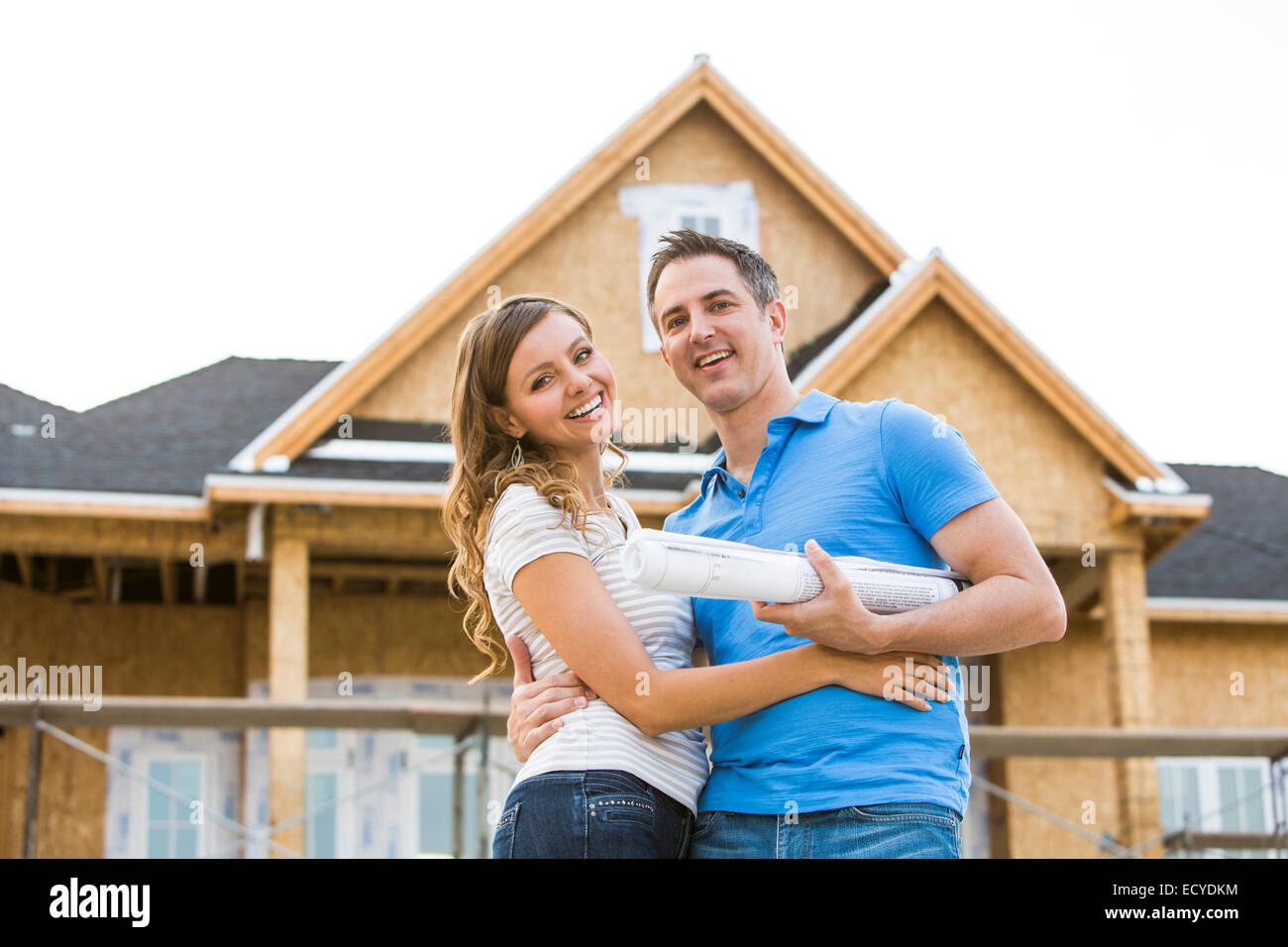 Caucasian couple hugging near house under construction Stock Photo - Alamy