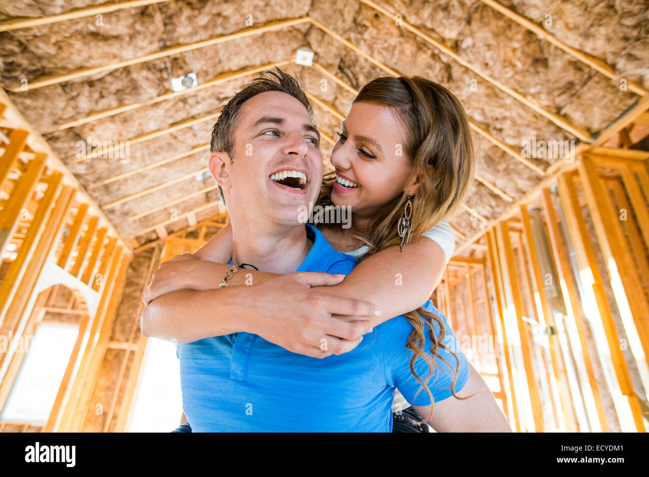 Caucasian couple hugging in house under construction Stock Photo - Alamy