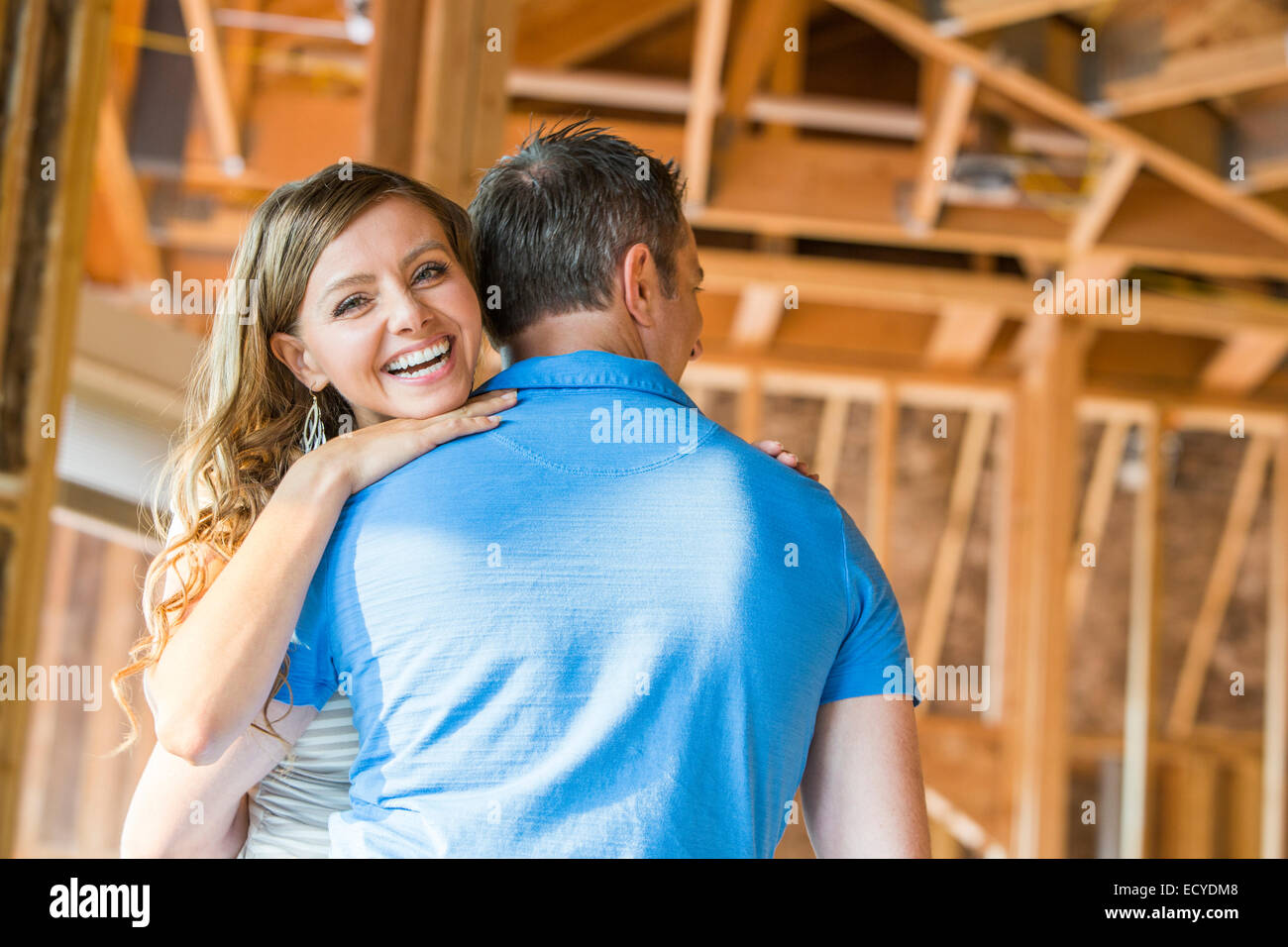 Caucasian couple hugging in house under construction Stock Photo - Alamy