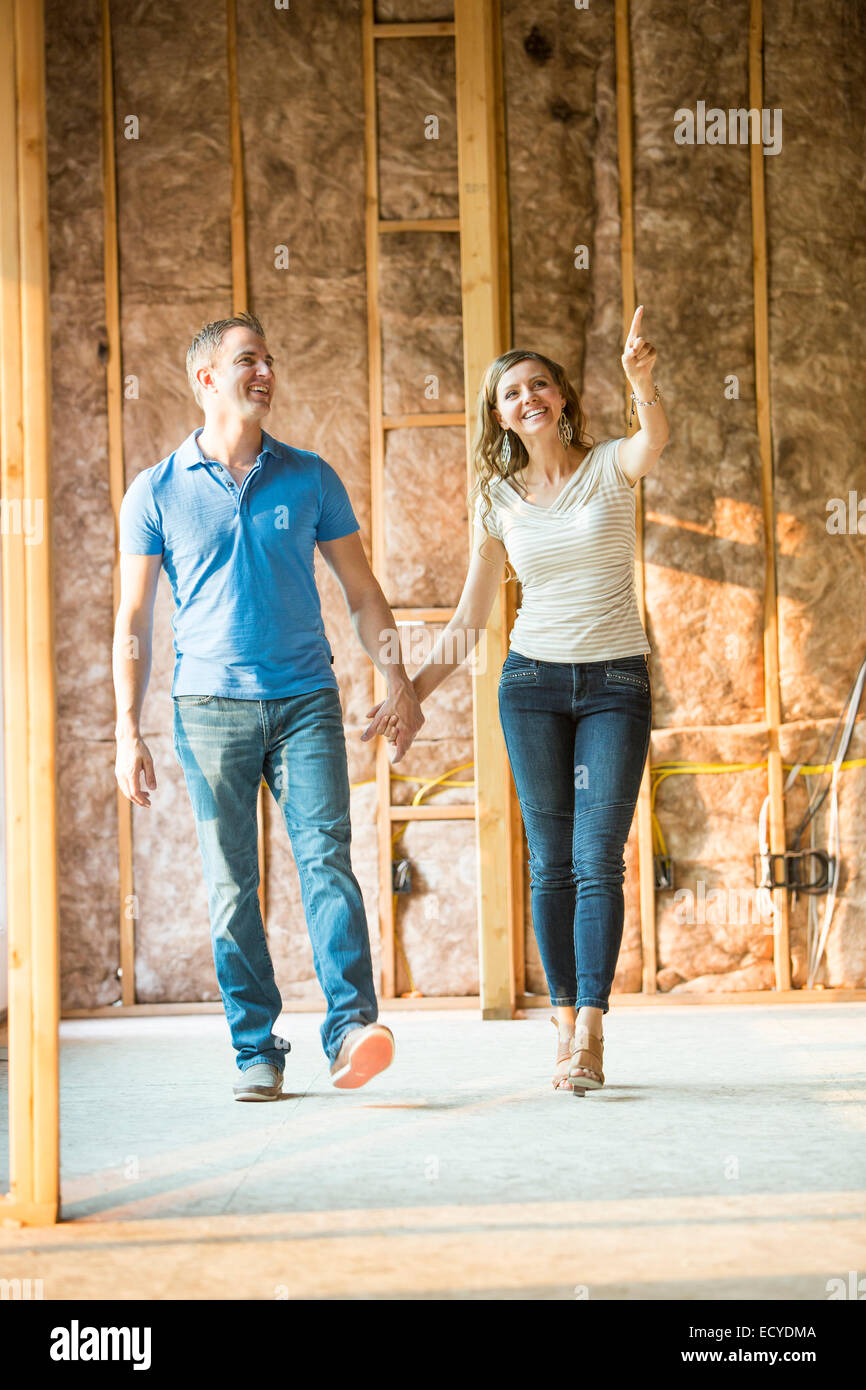 Caucasian couple walking in house under construction Stock Photo - Alamy