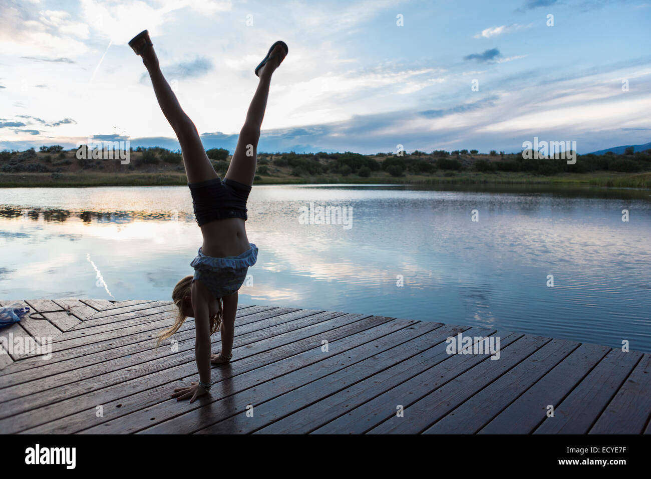 Caucasian girl doing handstand on wooden deck near lake Stock Photo - Alamy