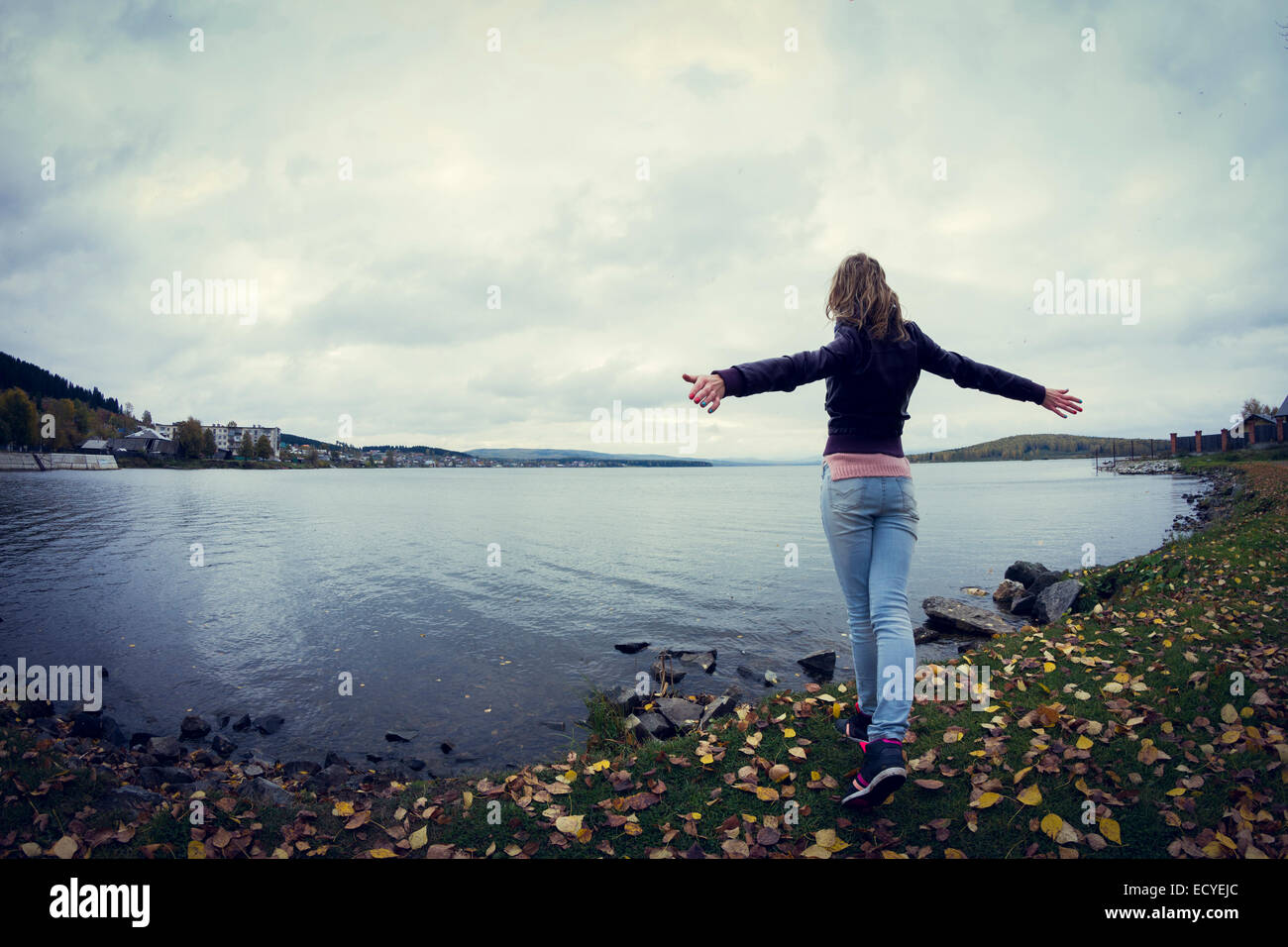 Woman standing with arms outstretched near lake Stock Photo - Alamy