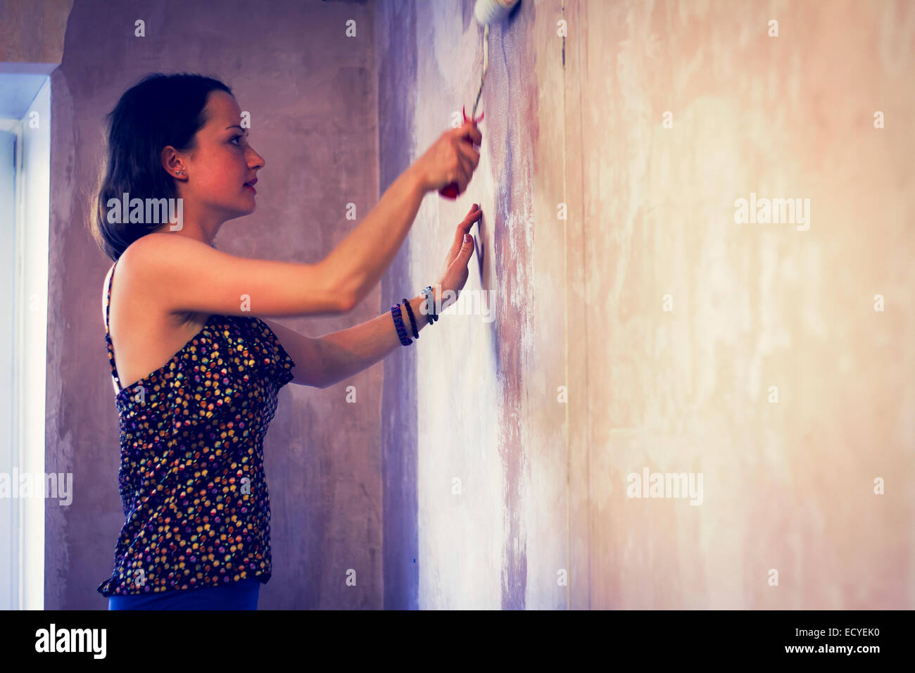 Woman painting wall with paint roller Stock Photo - Alamy