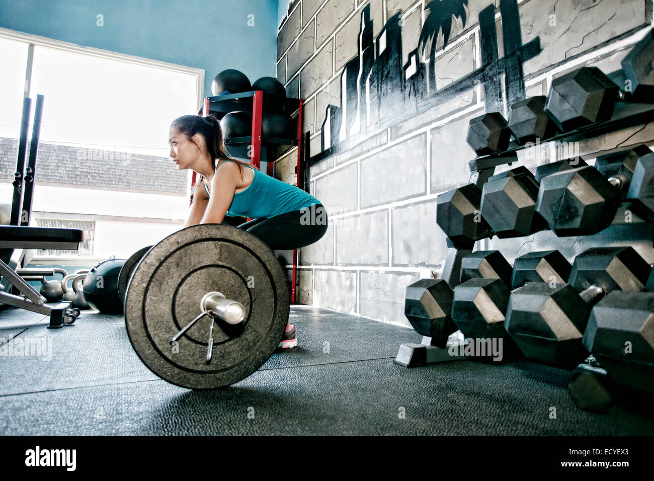 Mixed race woman lifting weights in gym Stock Photo - Alamy