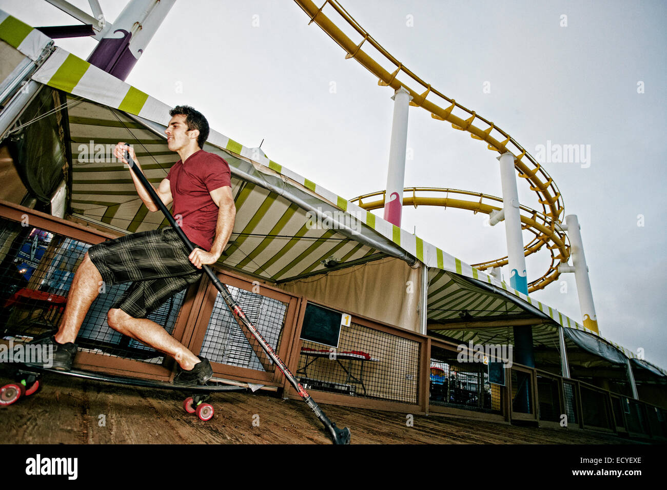 Caucasian man skateboarding with paddle pole at amusement park Stock ...