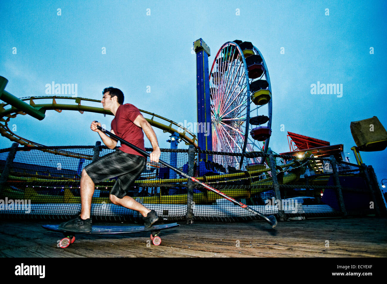 Caucasian man skateboarding with paddle pole at amusement park Stock ...