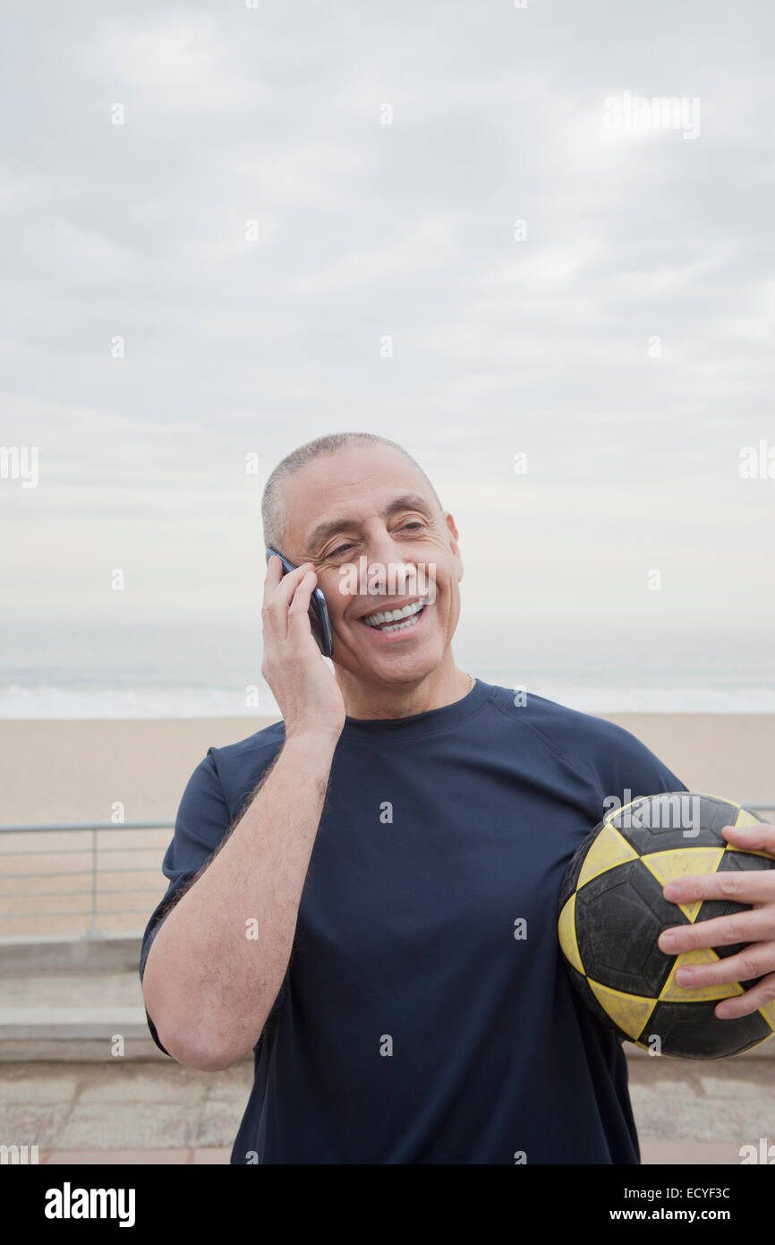 Hispanic senior man with soccer ball talking on cell phone Stock Photo ...