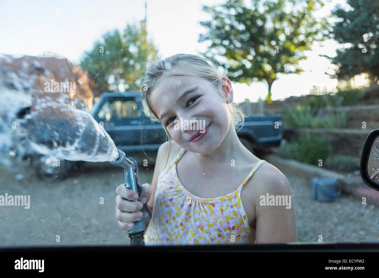 Caucasian girl spraying water from hose outdoors Stock Photo - Alamy