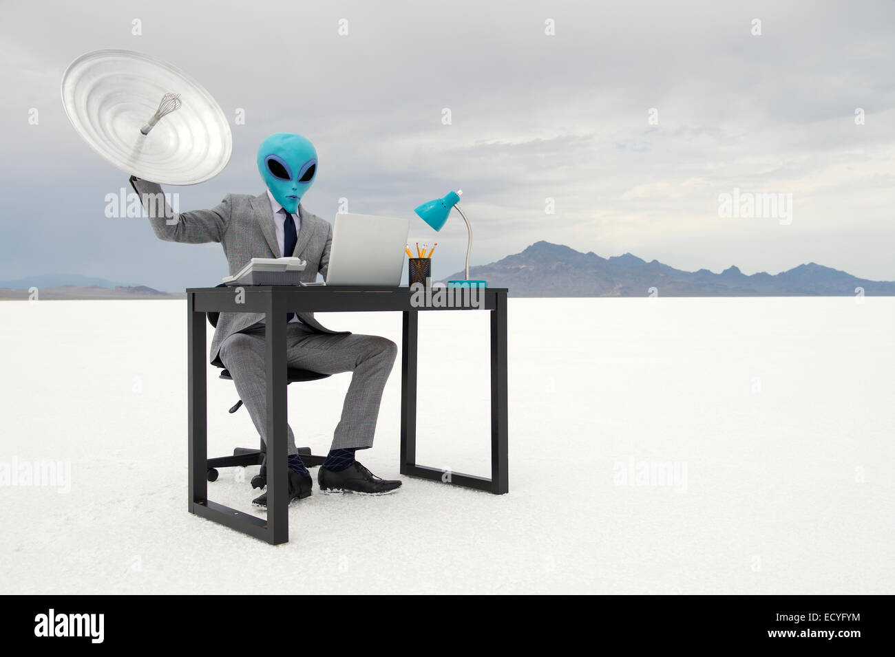 Alien businessman sitting at his office desk trying to communicate ...