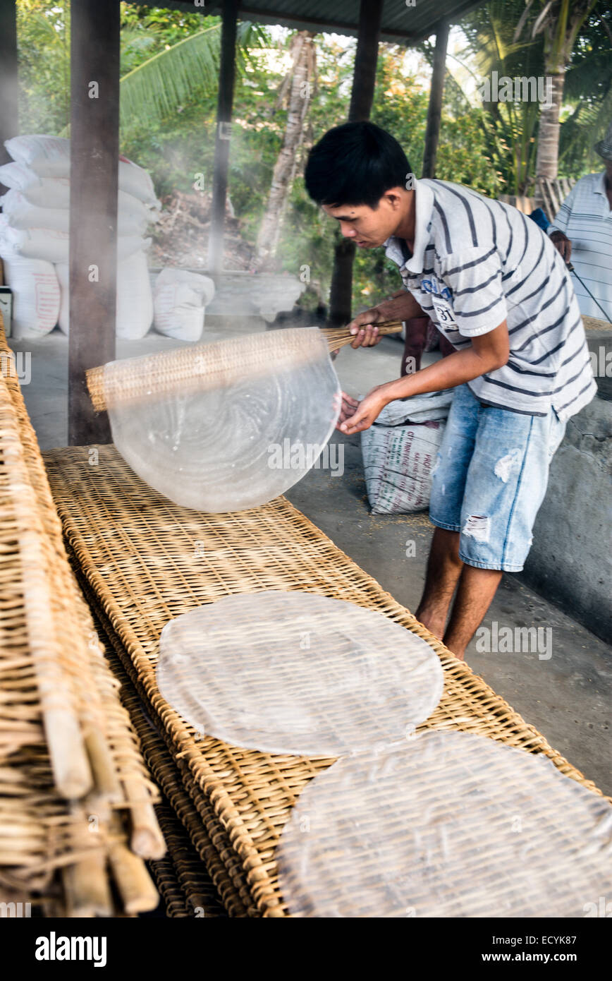 Vietnamese family working in their small home factory making rice paper ...