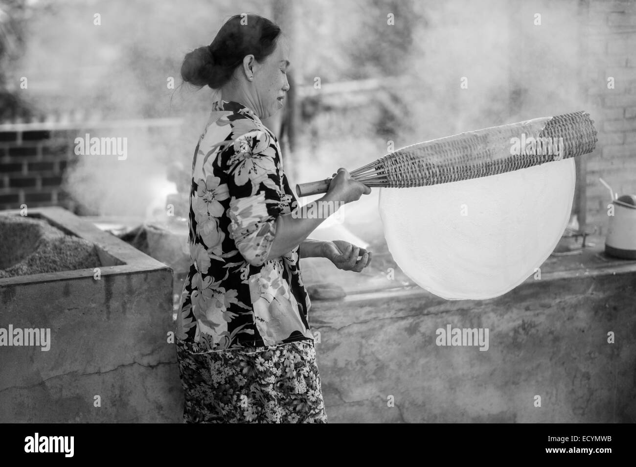 Vietnamese family working in their small home factory making rice paper ...