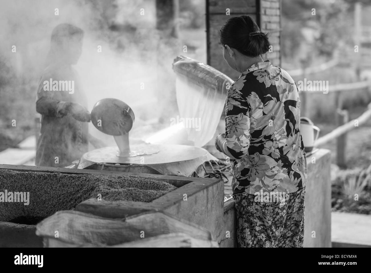 Vietnamese family working in their small home factory making rice paper ...